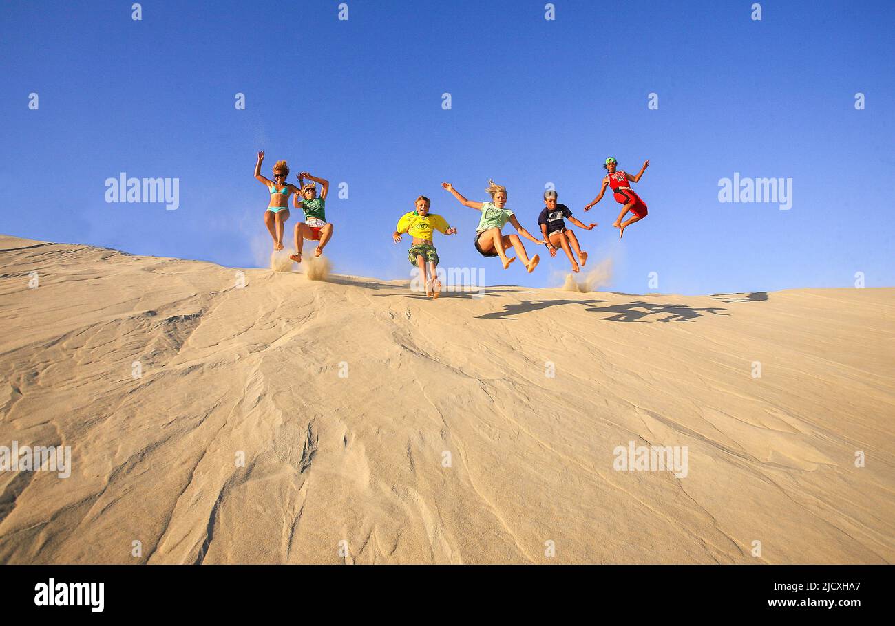 Brazil, Jericoacoara Children enjoying jumping off a huge sand dune on ...