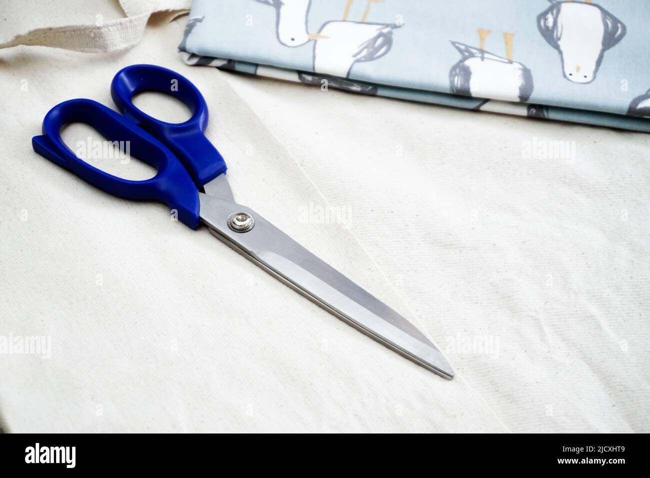 White fabric and blue scissor on isolated background close up view ...