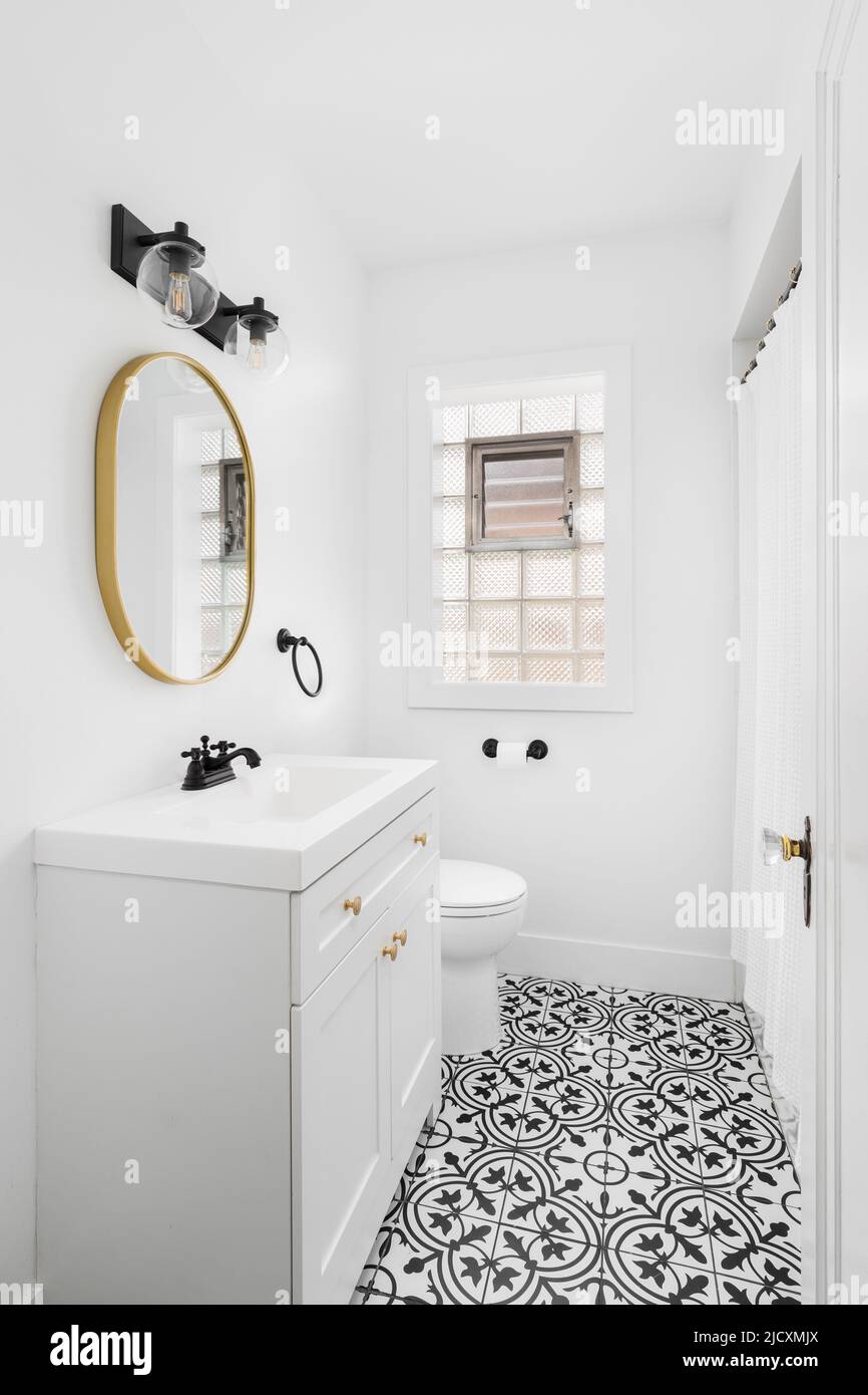 A bathroom with a white vanity cabinet, mosaic black and white tiled ...