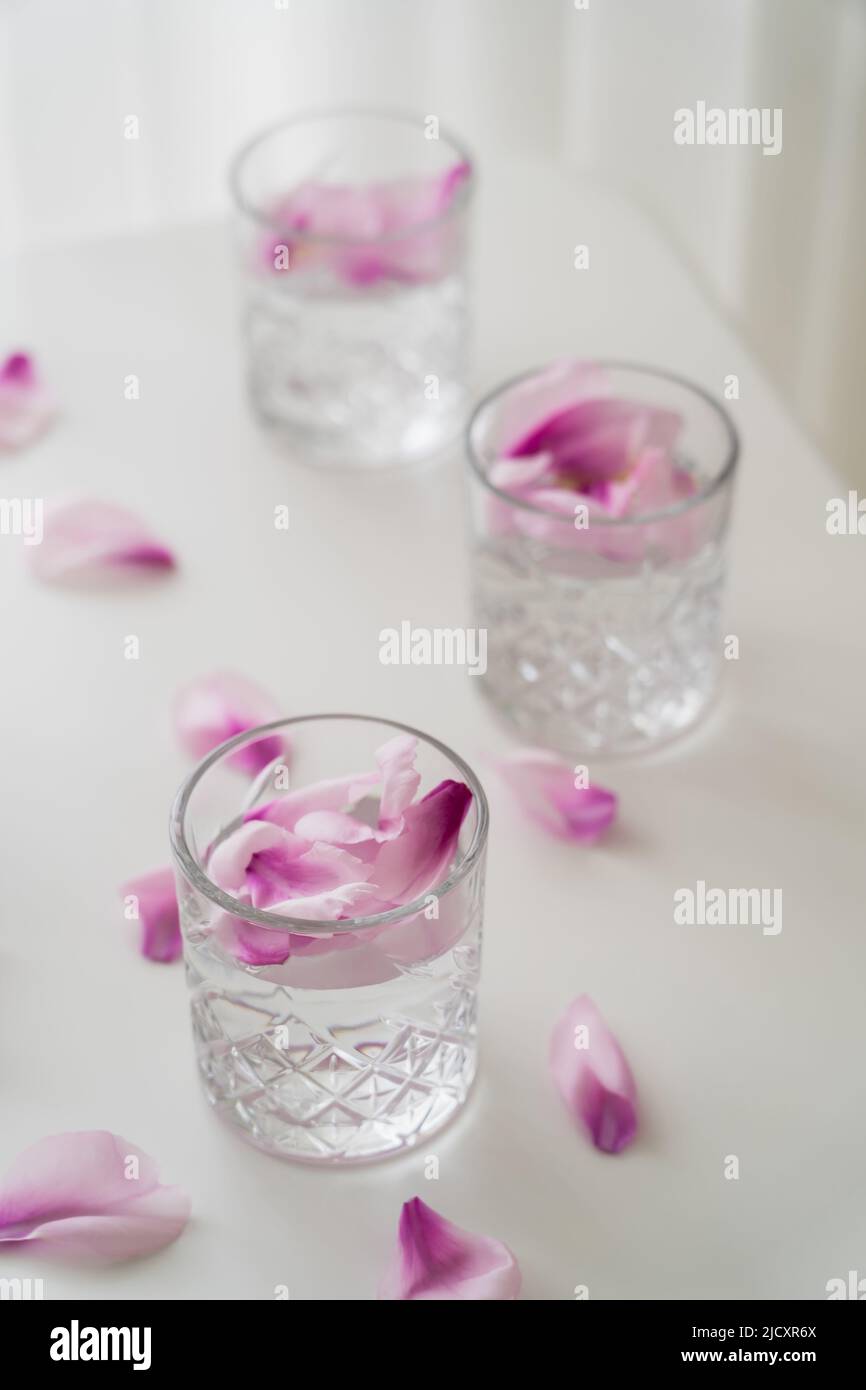 high angle view of faceted glasses with tonic and natural petals on ...