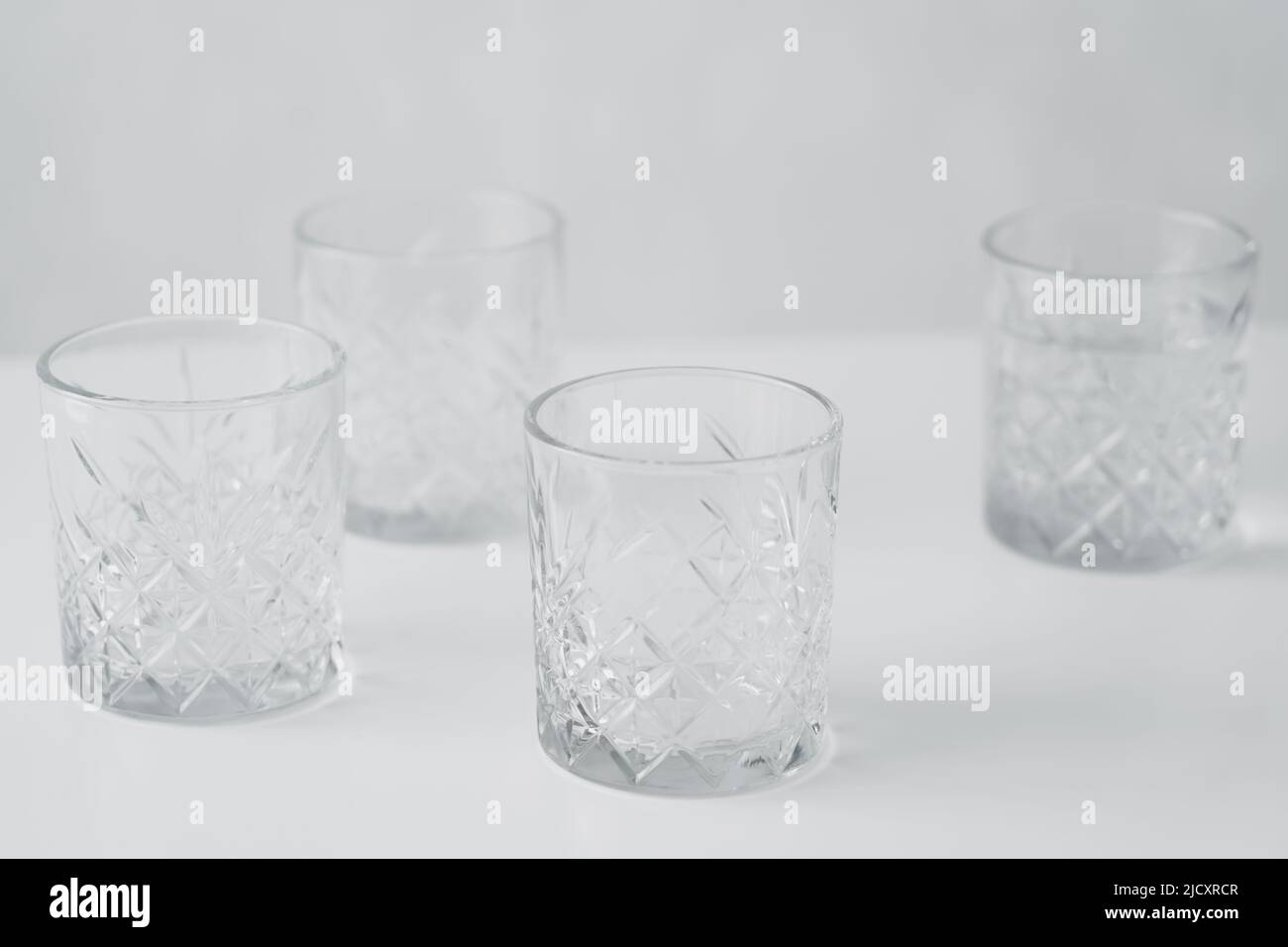 empty faceted crystal glasses on white tabletop isolated on grey Stock ...