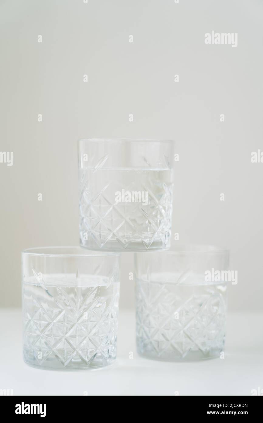 stack of crystal glasses with pure water on white surface isolated on ...