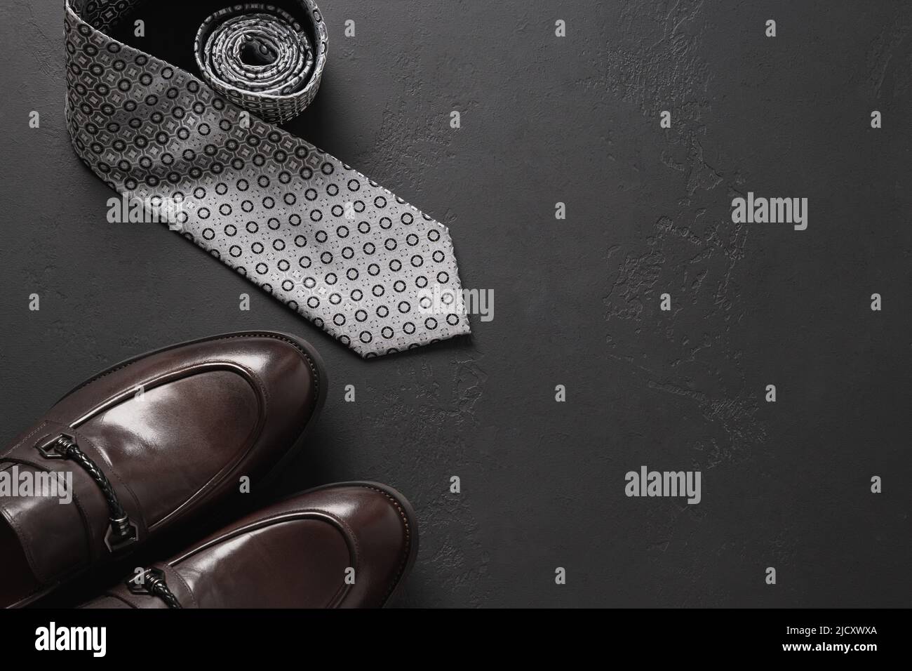 Men's accessories set - brown shoes, tie on black background. Top view ...