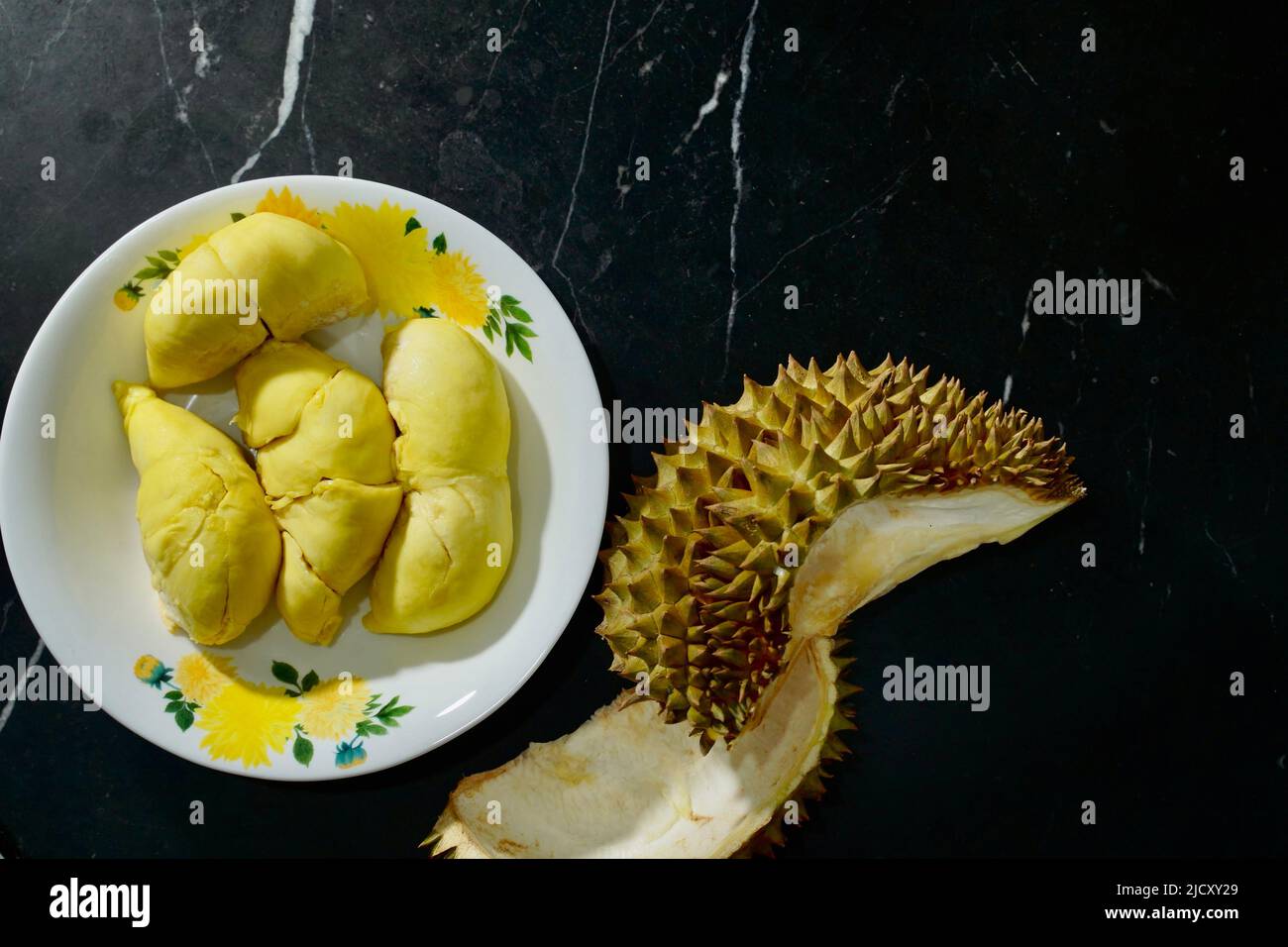 Fresh durian in packaging on white dish with durian peel on banner ...