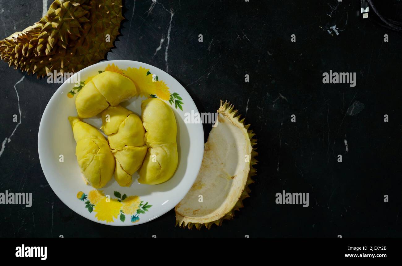 Fresh durian in packaging on white dish with durian peel on banner ...