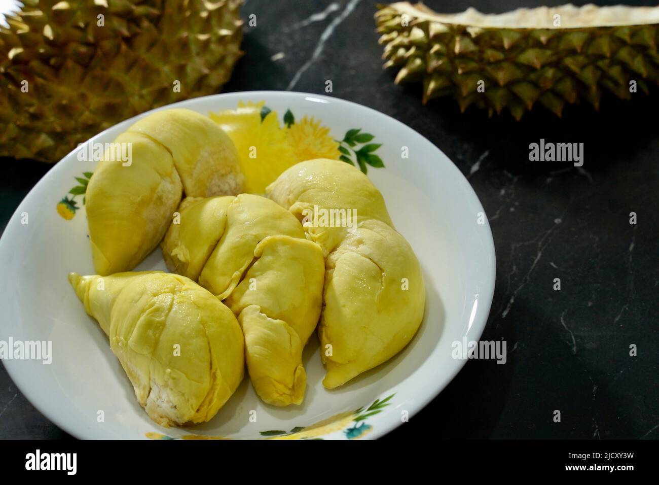 Fresh durian in packaging on white dish with durian peel on banner ...