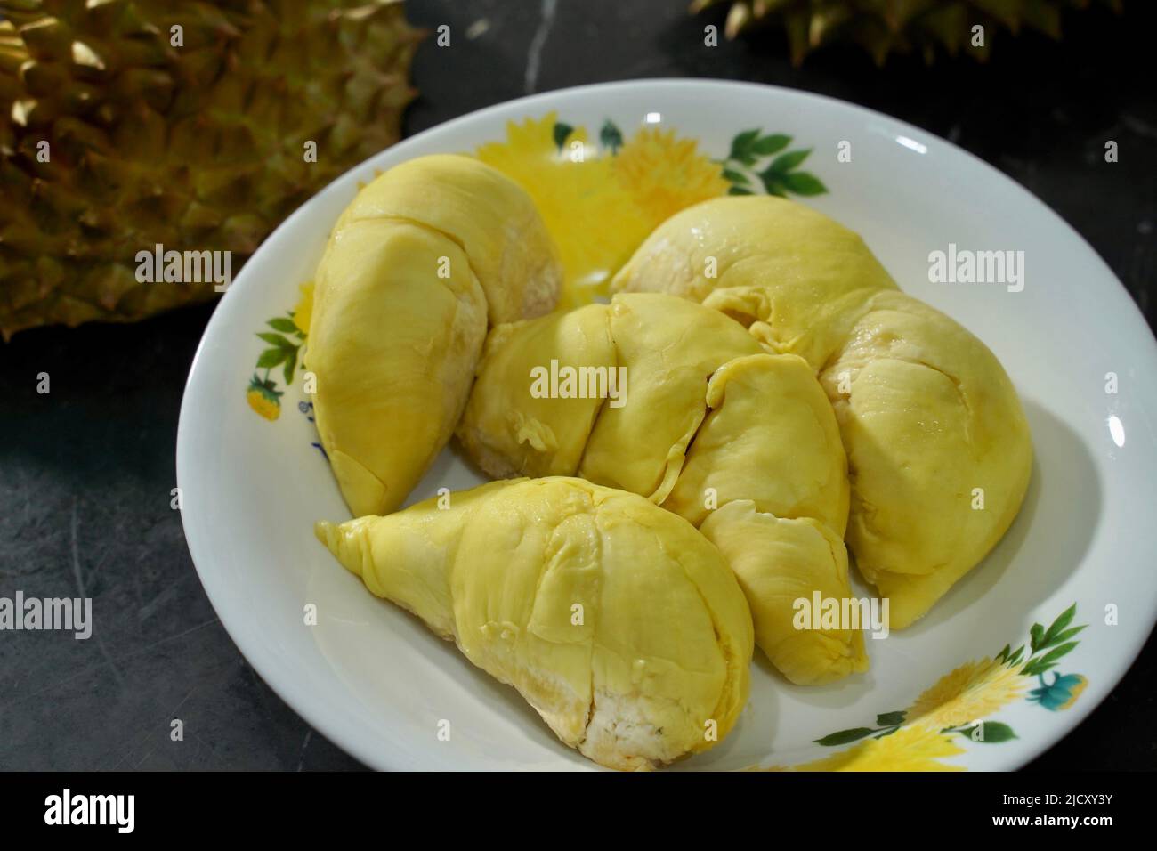 Fresh durian in packaging on white dish with durian peel on banner ...