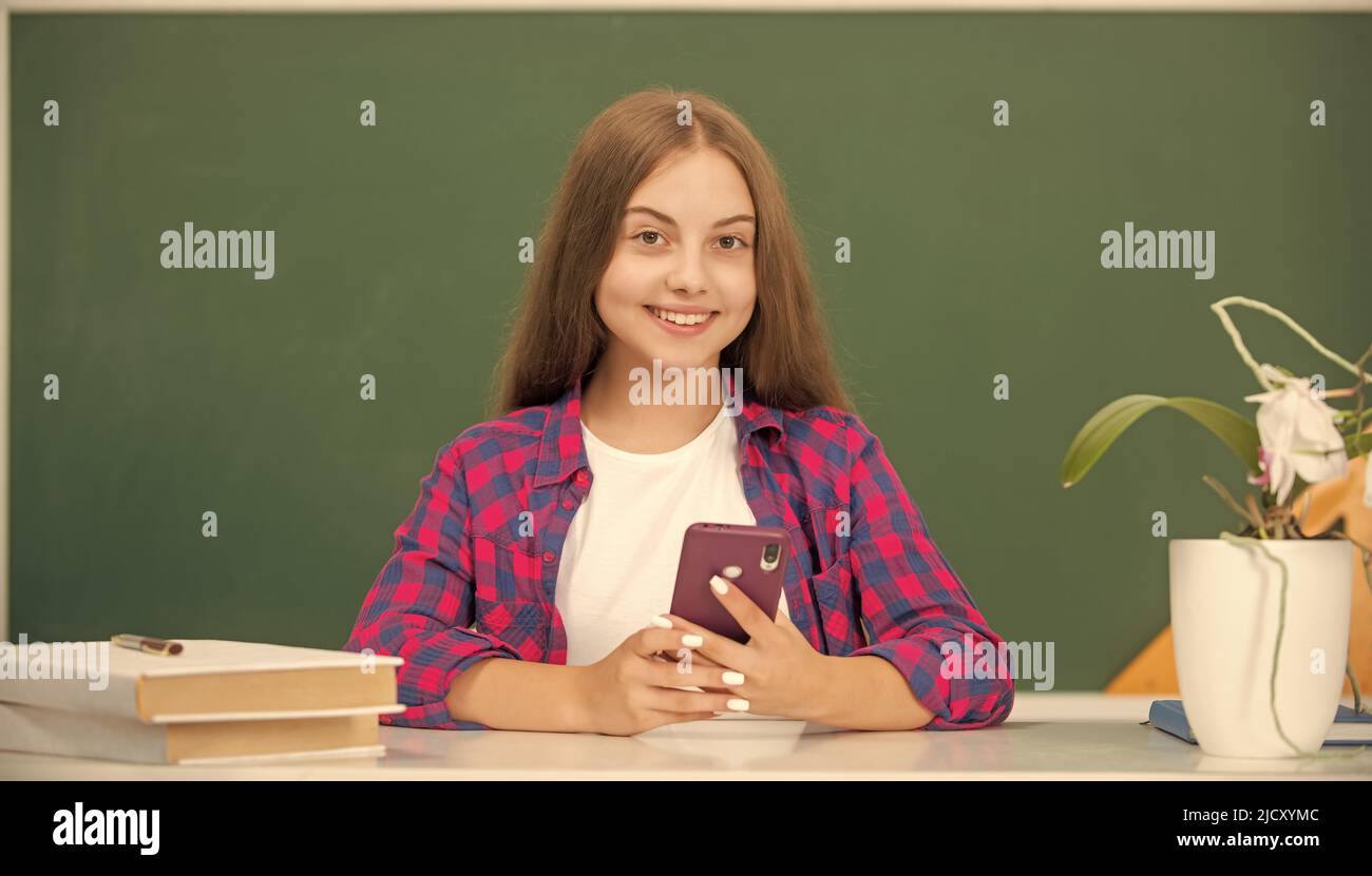 happy teen girl typing message on mobile phone in high school at ...