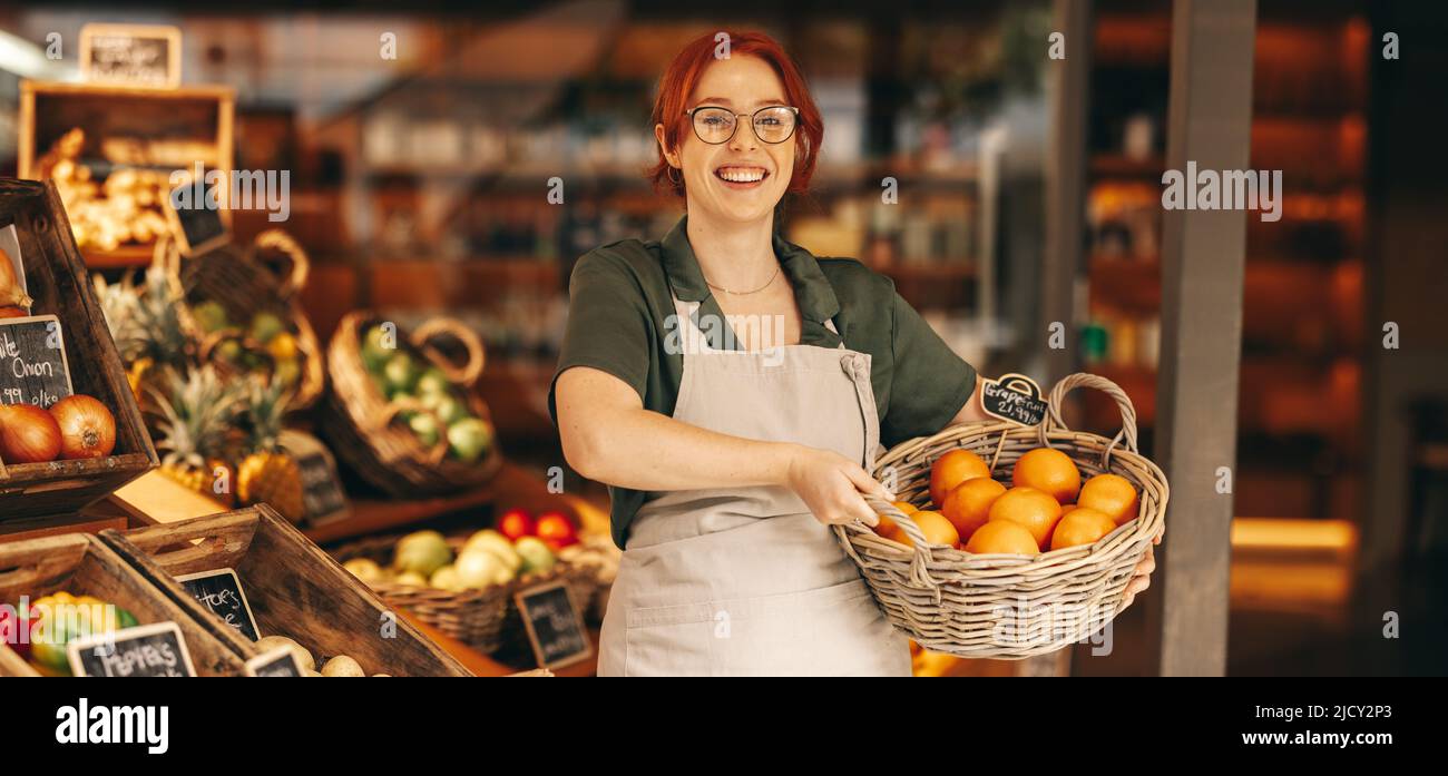 Happy grocery store owner smiling at the camera while holding a basket ...