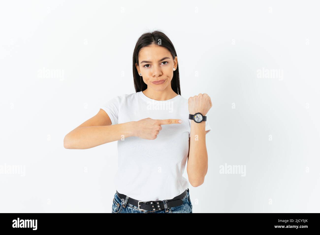 Portrait of disappointed young woman points to the clock with ...