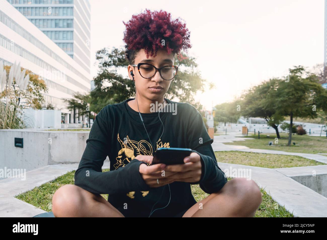 brunette young latin woman with afro, dressed in black, sitting cross ...