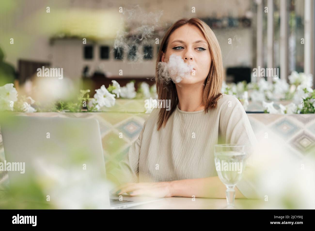 Young Woman Smoking Electronic Cigarette in the Restaurant While ...