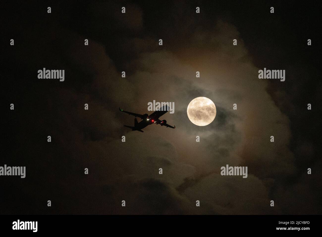 Aircraft flying in path of full moon at night Stock Photo - Alamy