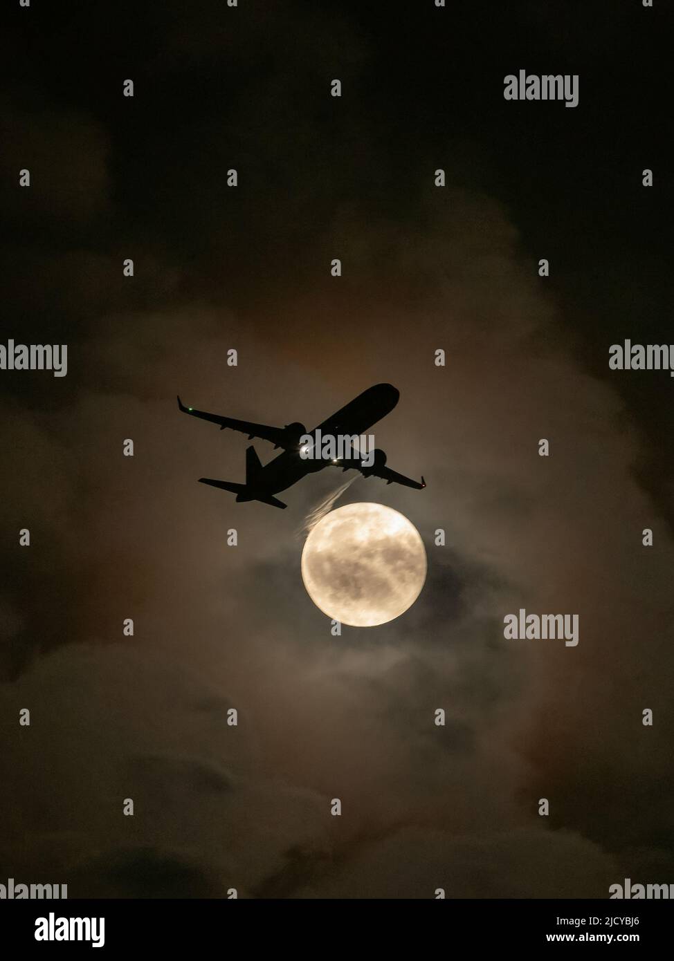 Aircraft flying in path of full moon at night Stock Photo - Alamy