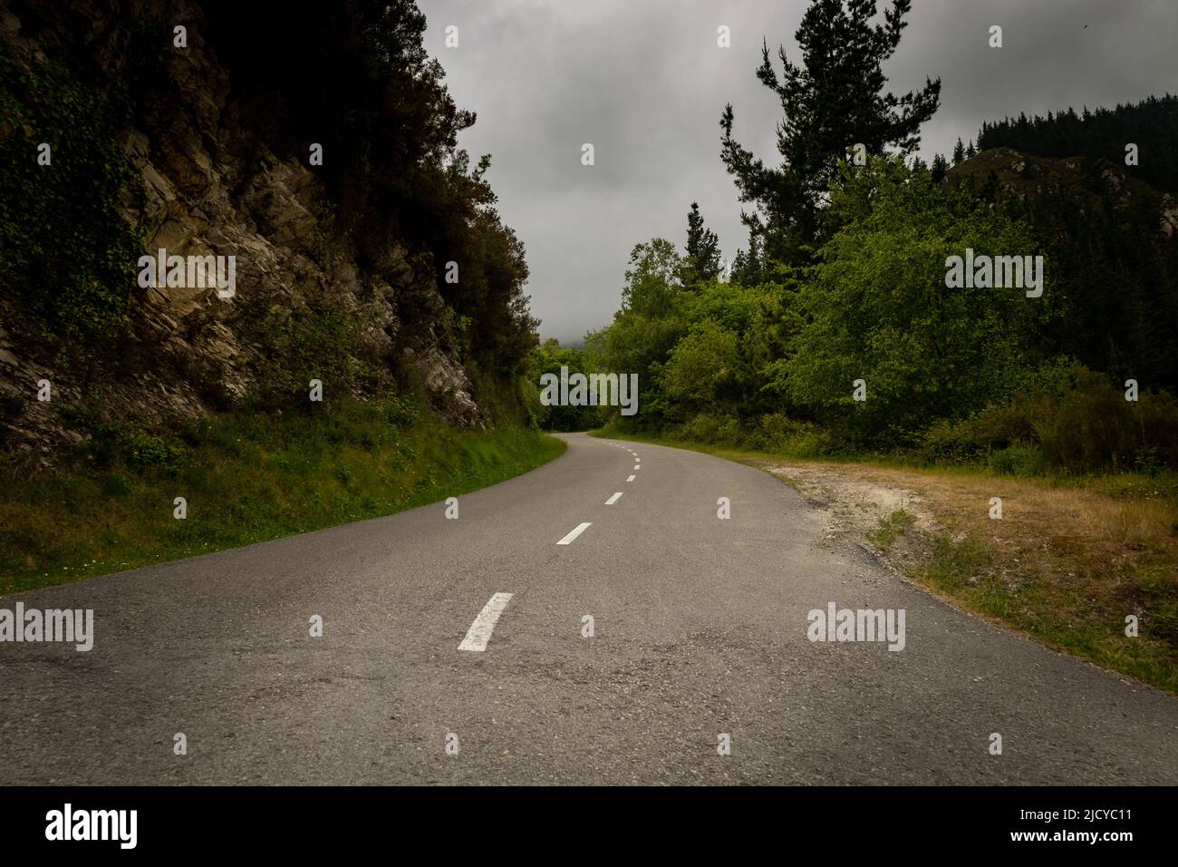 Desolate winding road in the mountains with lots of vegetation ...