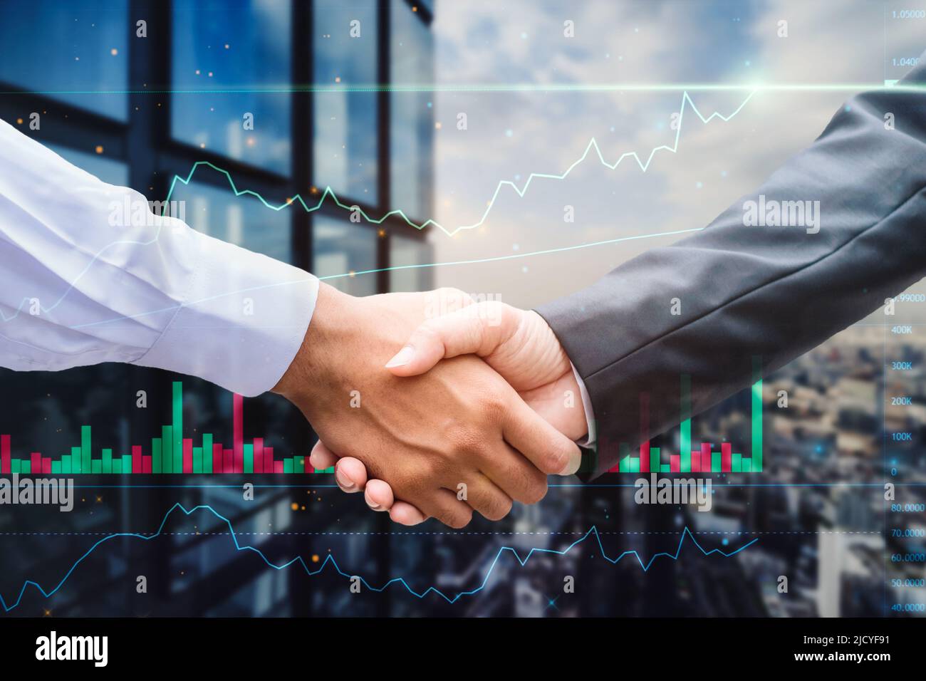 Businessman partnership handshake together on technical trading graph ...