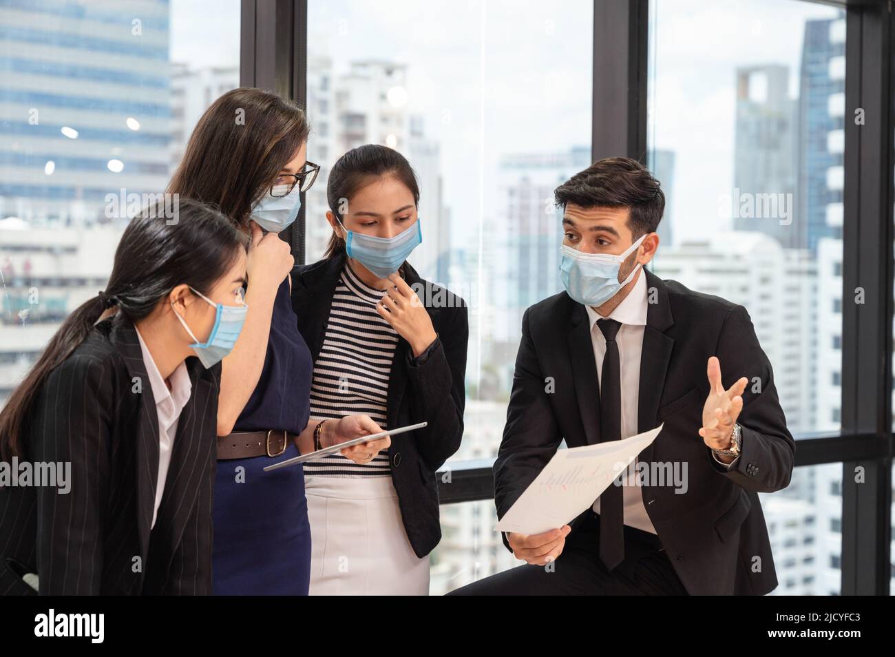 Multiethnic business team wearing face mask during business meeting in ...