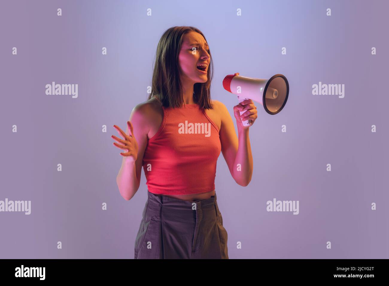 Excited young beautiful girl shouting at megaphone isolated on gradient ...