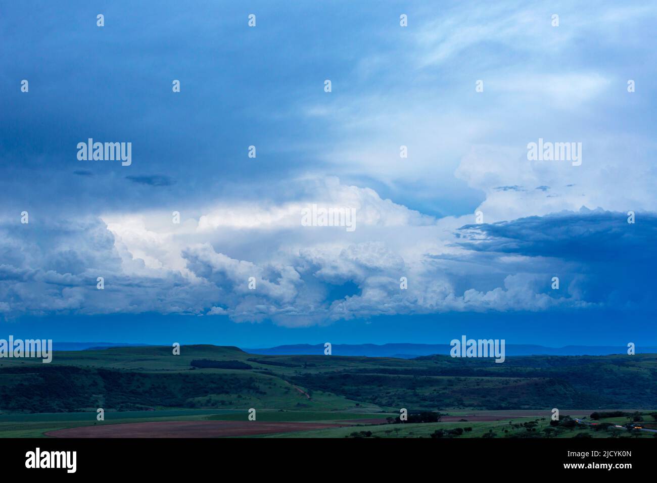Blue sky and white cumulus clouds over green landscape after sunset ...