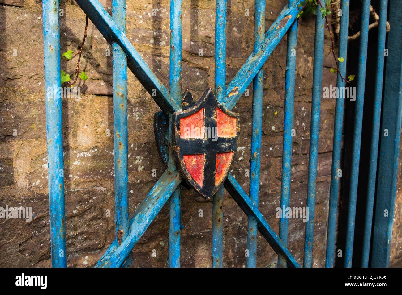 blue painted iron gate with a black and red coat of arms with a ...