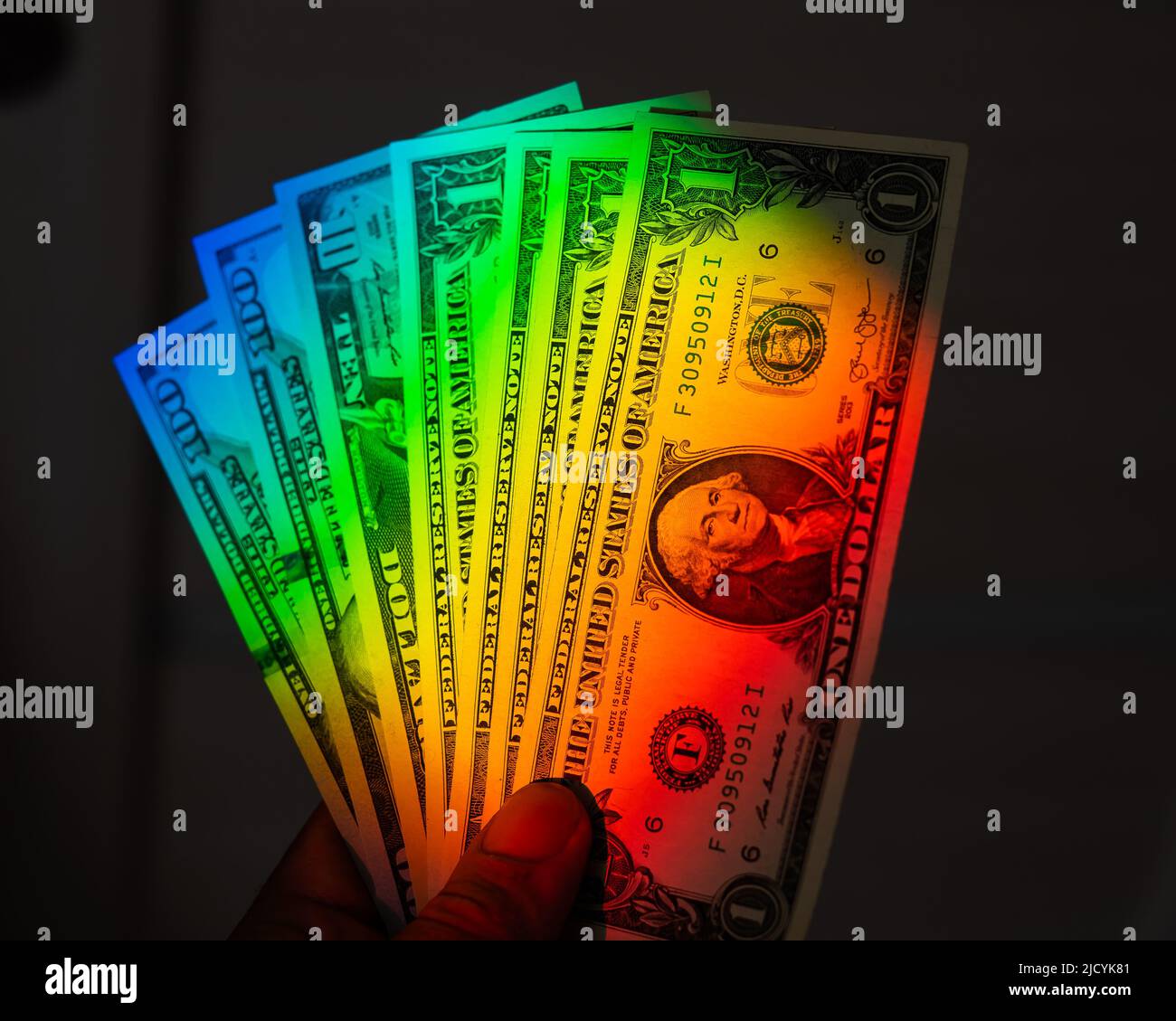 Rays of a rainbow on a man's hand with a bundle of dollars Stock Photo ...