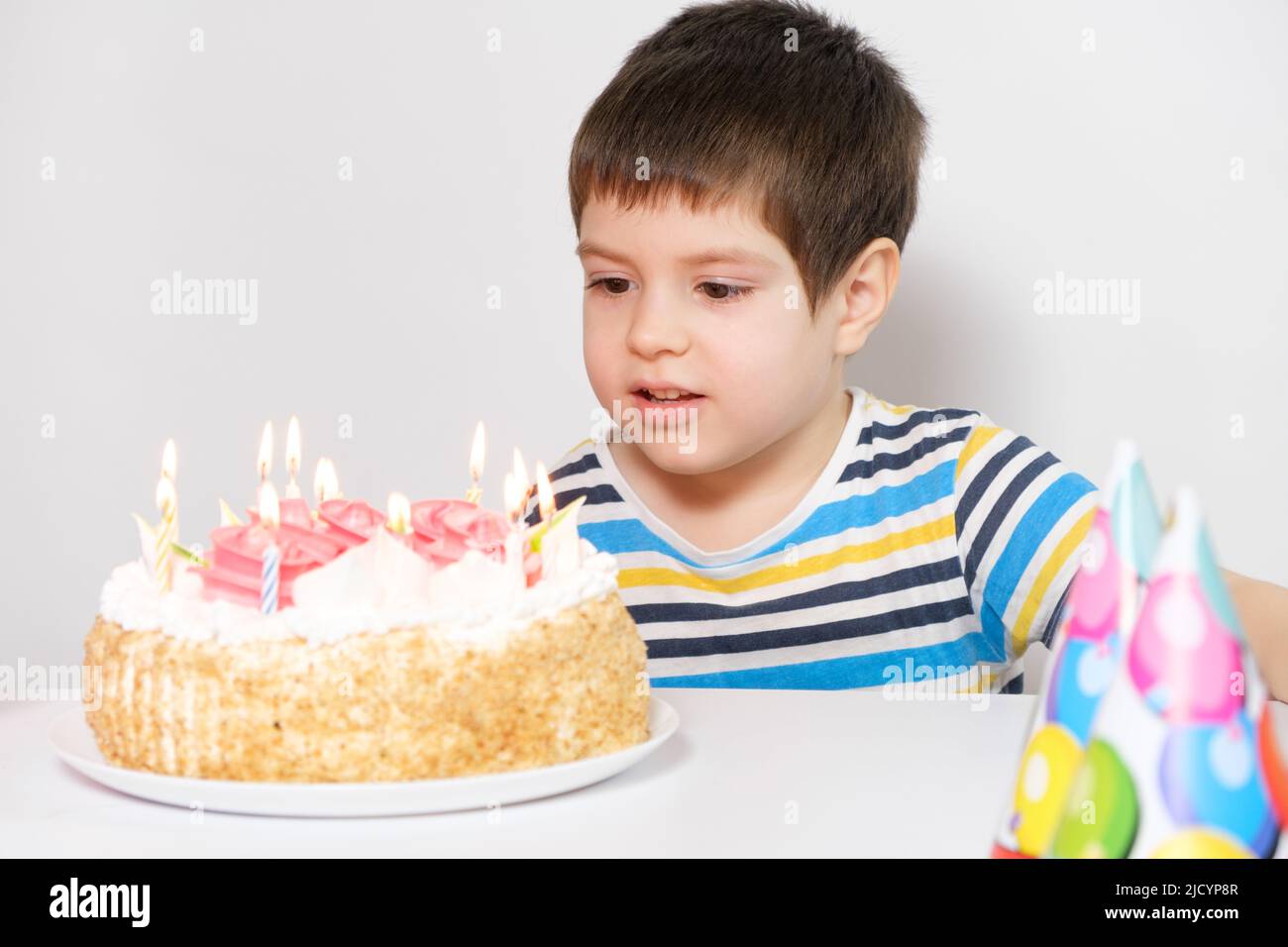 A boy celebrates his birthday sitting at a table on a white background ...