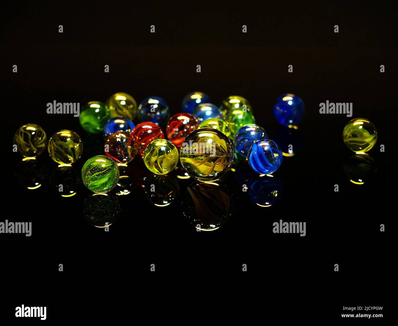 Colorful marbles shot in a black background, above light illumination ...