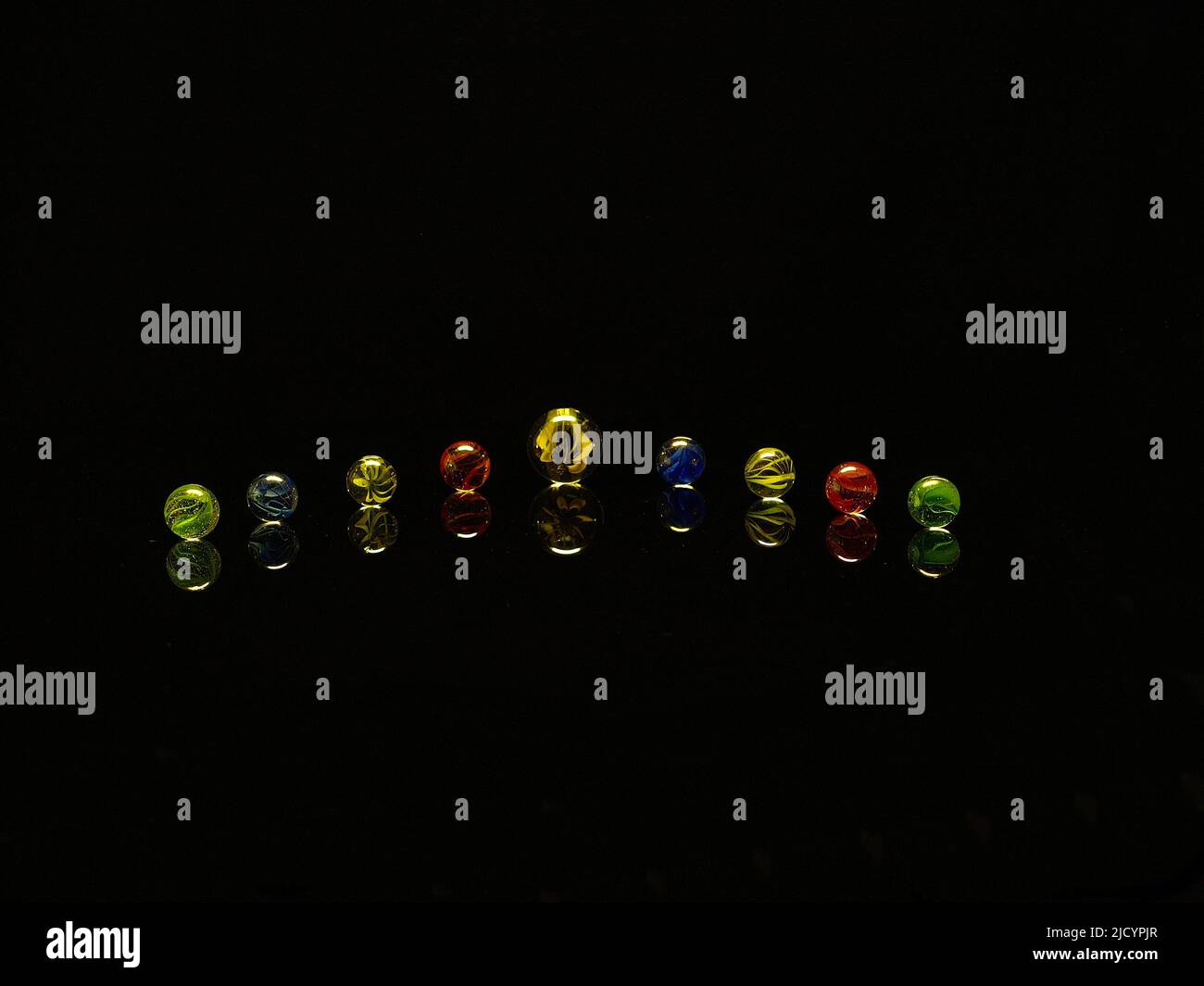 Colorful marbles shot in a black background, above light illumination ...