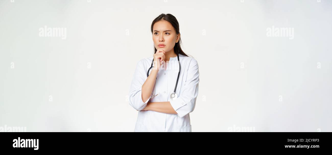 Image of serious doctor, female healthcare worker thinking, looking ...