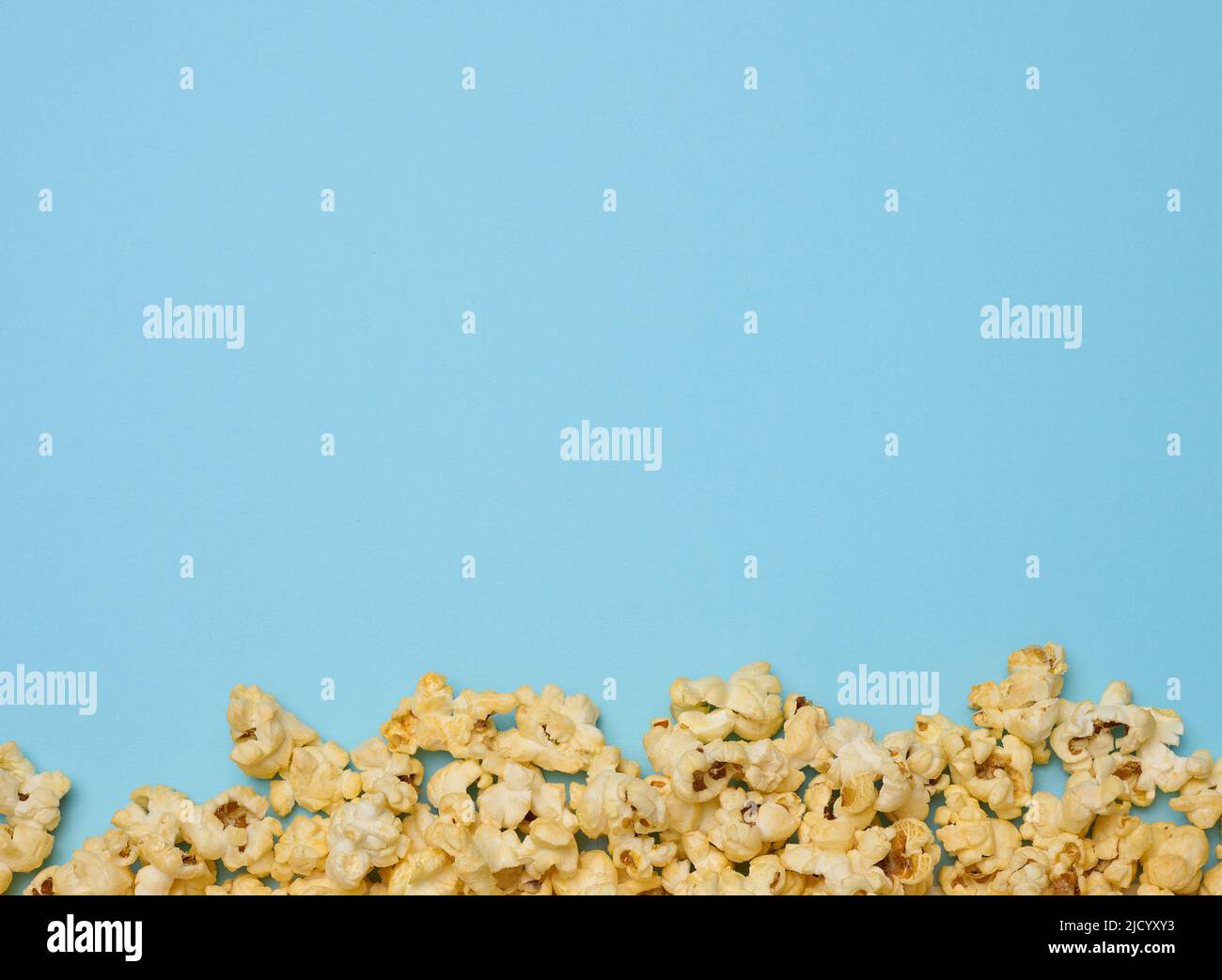 Heap of fried popcorn with cheese on a blue background, top view. Copy ...