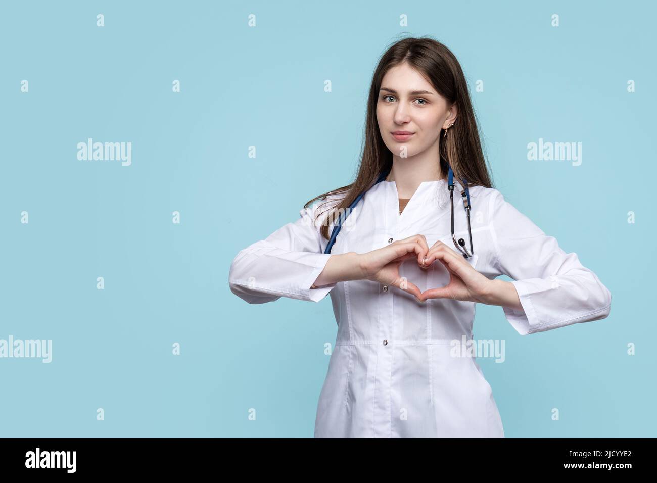 Female Intern Doctor posing blue background studio. Heart shaped ...