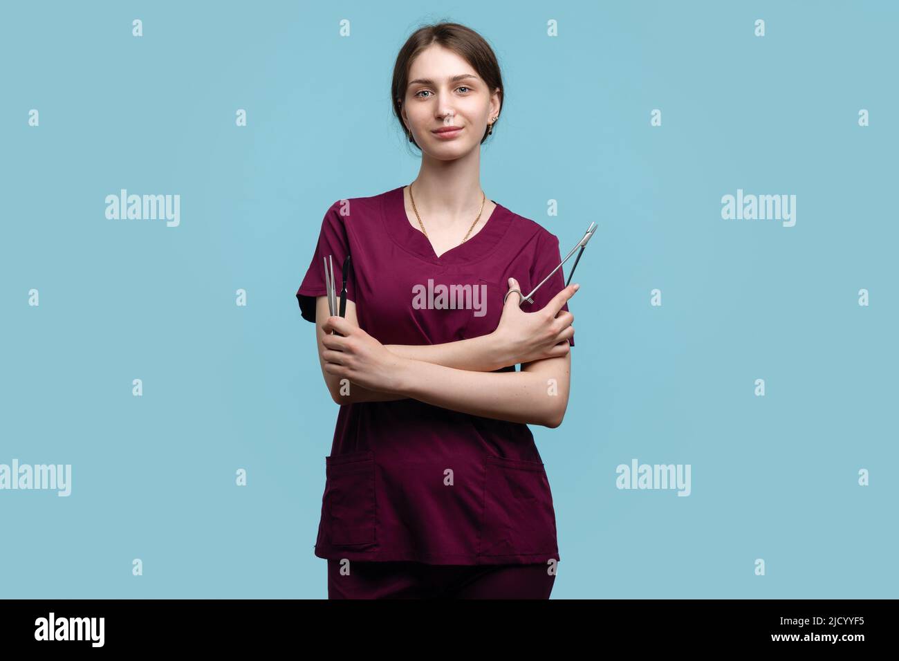 Young Female Surgeon Posing with Steel Surgical Instruments on blue ...