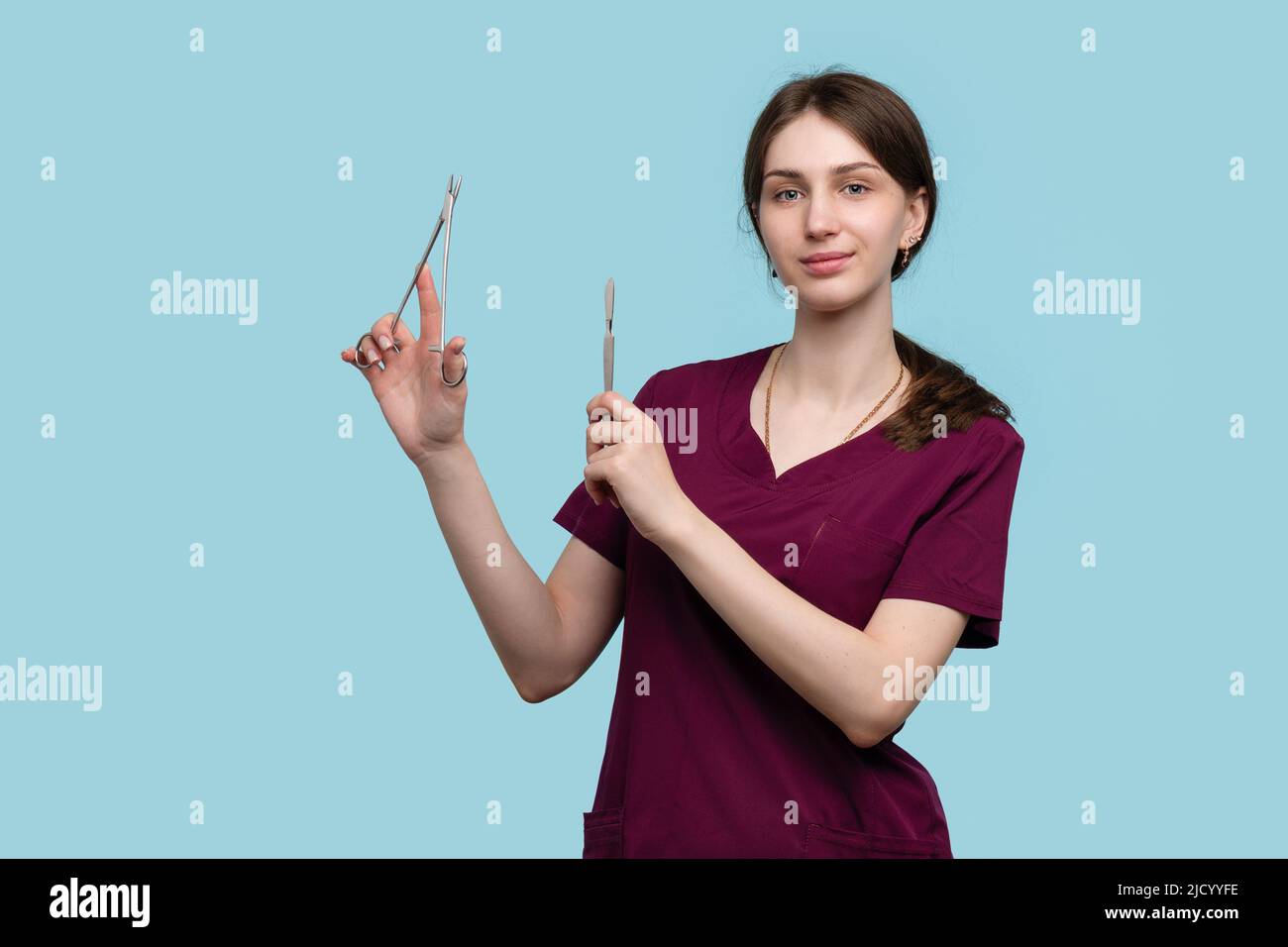Young Female Surgeon Posing with Steel Surgical Instruments on blue ...
