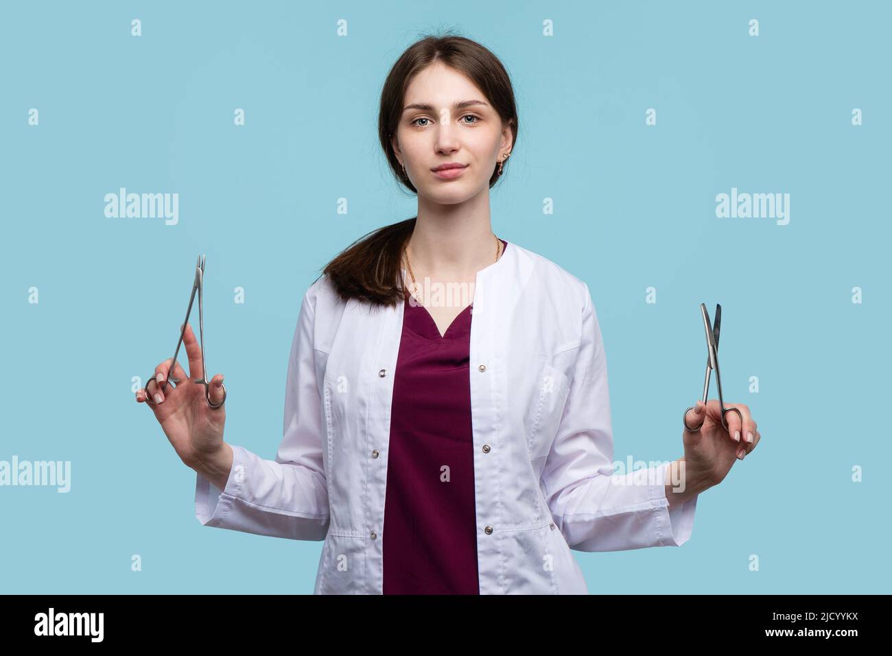 Young Female Surgeon Posing with Steel Surgical Instruments on blue ...