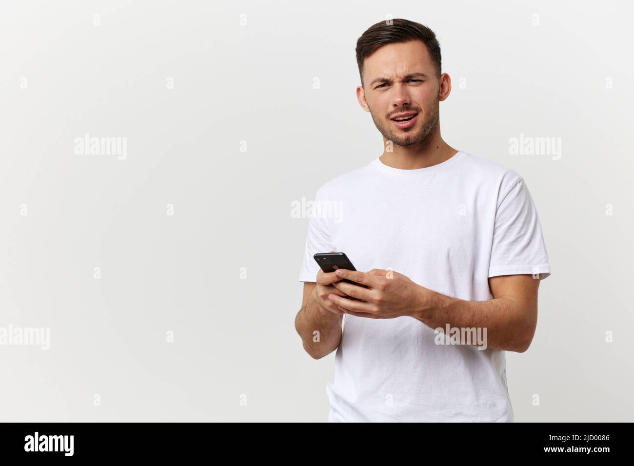 Shocked confused tanned handsome man in basic t-shirt get fake message ...