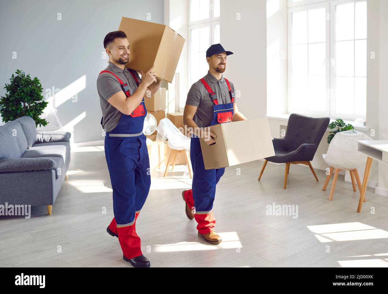 Two workers from moving and delivery service removing cardboard boxes ...