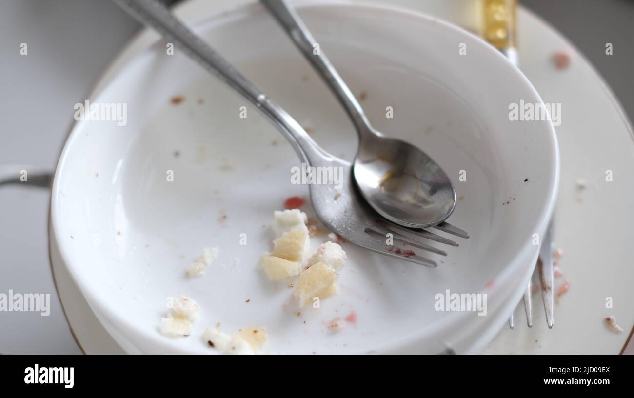 Dirty dishes close-up, spoon, fork, plates with food leftovers stacked ...