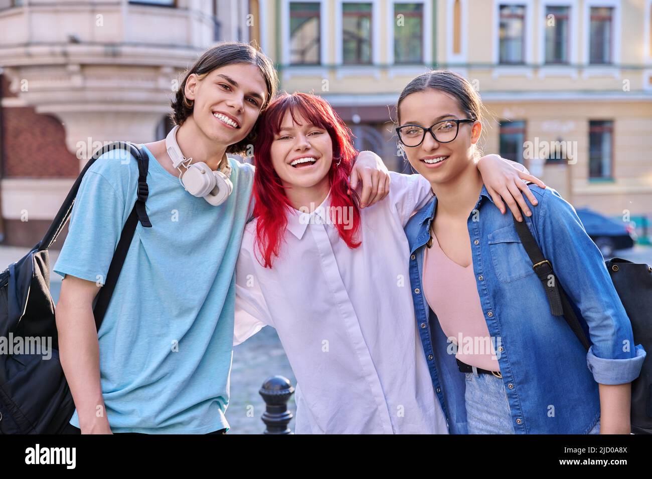 Happy smiling teenage friends hugging, looking at camera outdoor, on ...