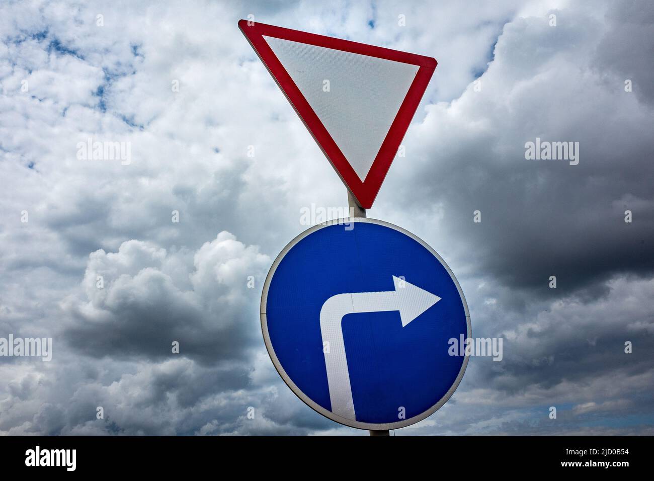 Road signs "Give way" and "Turn right" against the background of clouds ...