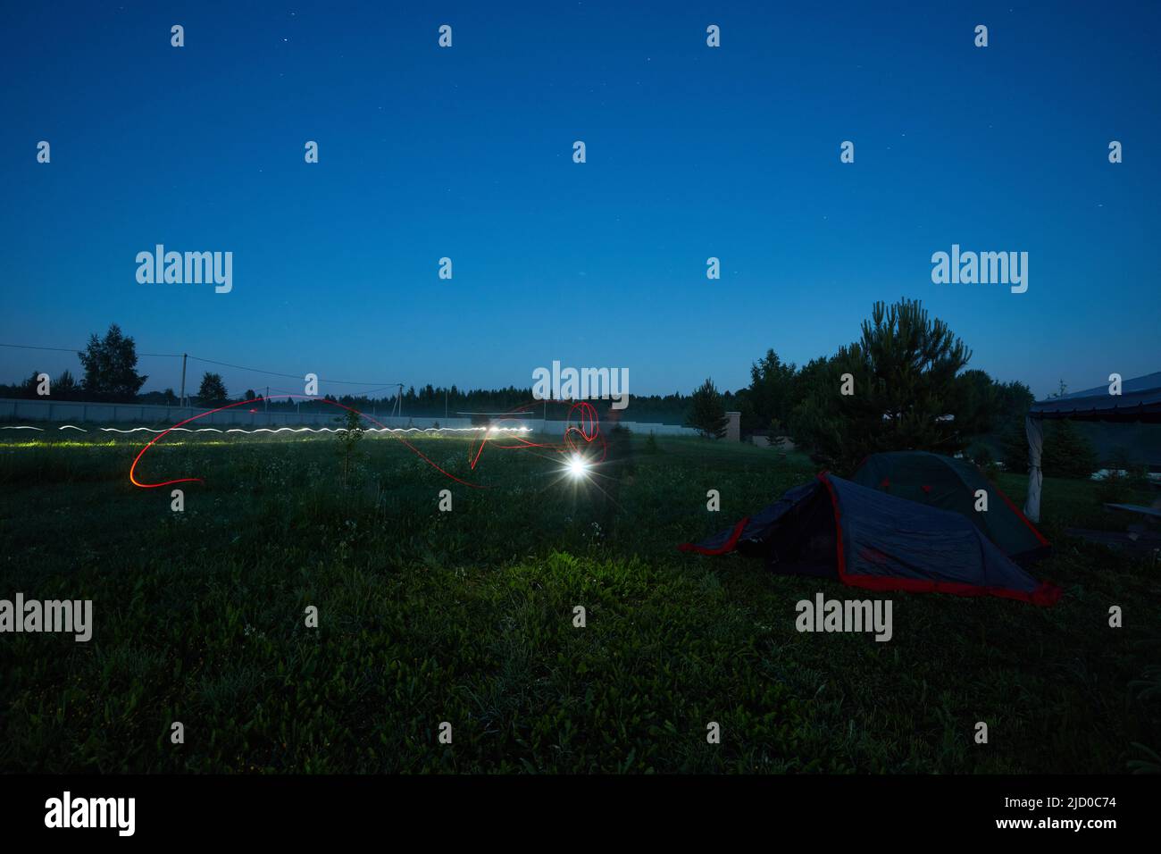 Man with a flashlight in a field at night Stock Photo - Alamy