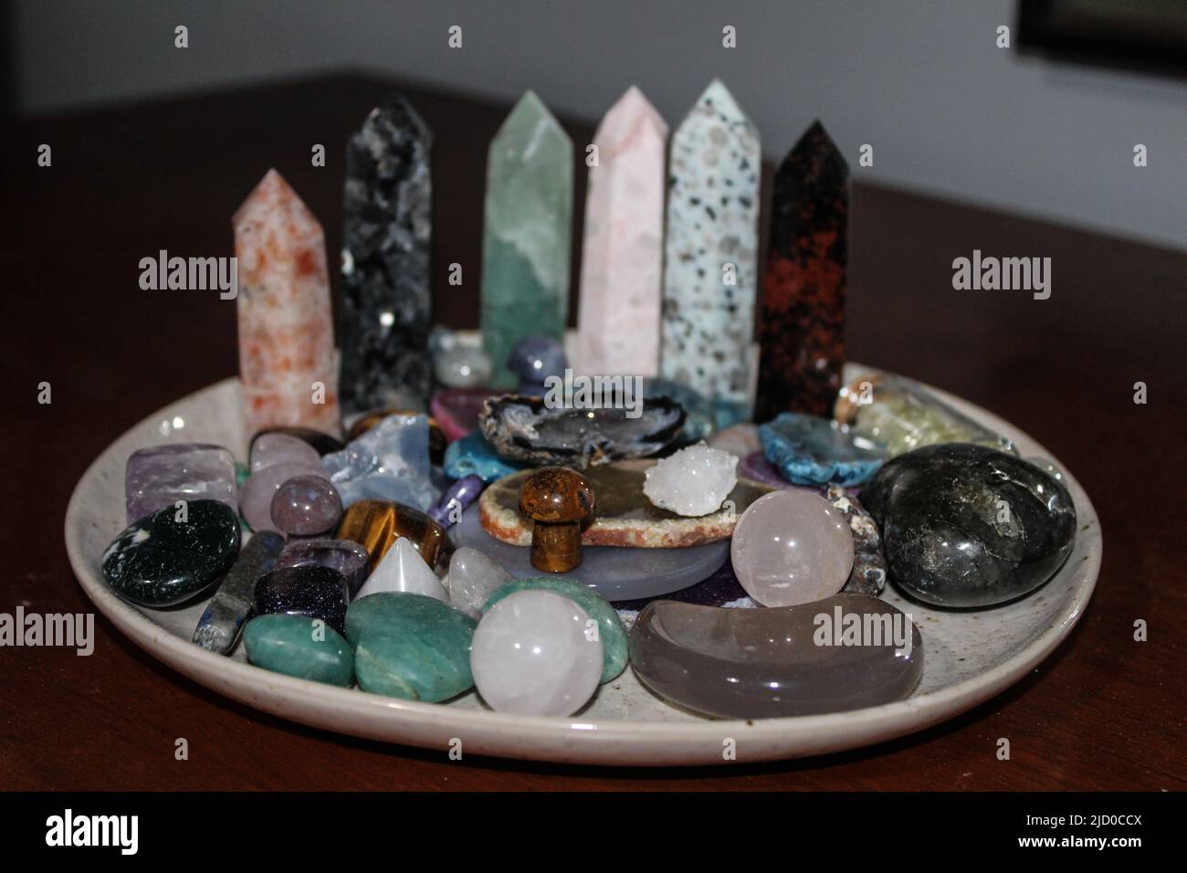 Crystals, tumbles and gemstones towers on wooden table. Minerals for ...