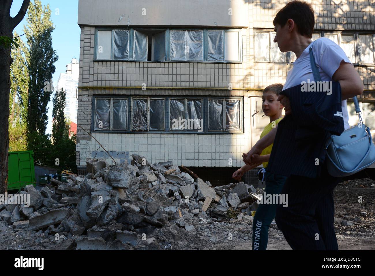 Residents walk past residential building destroyed, by a Russian ...