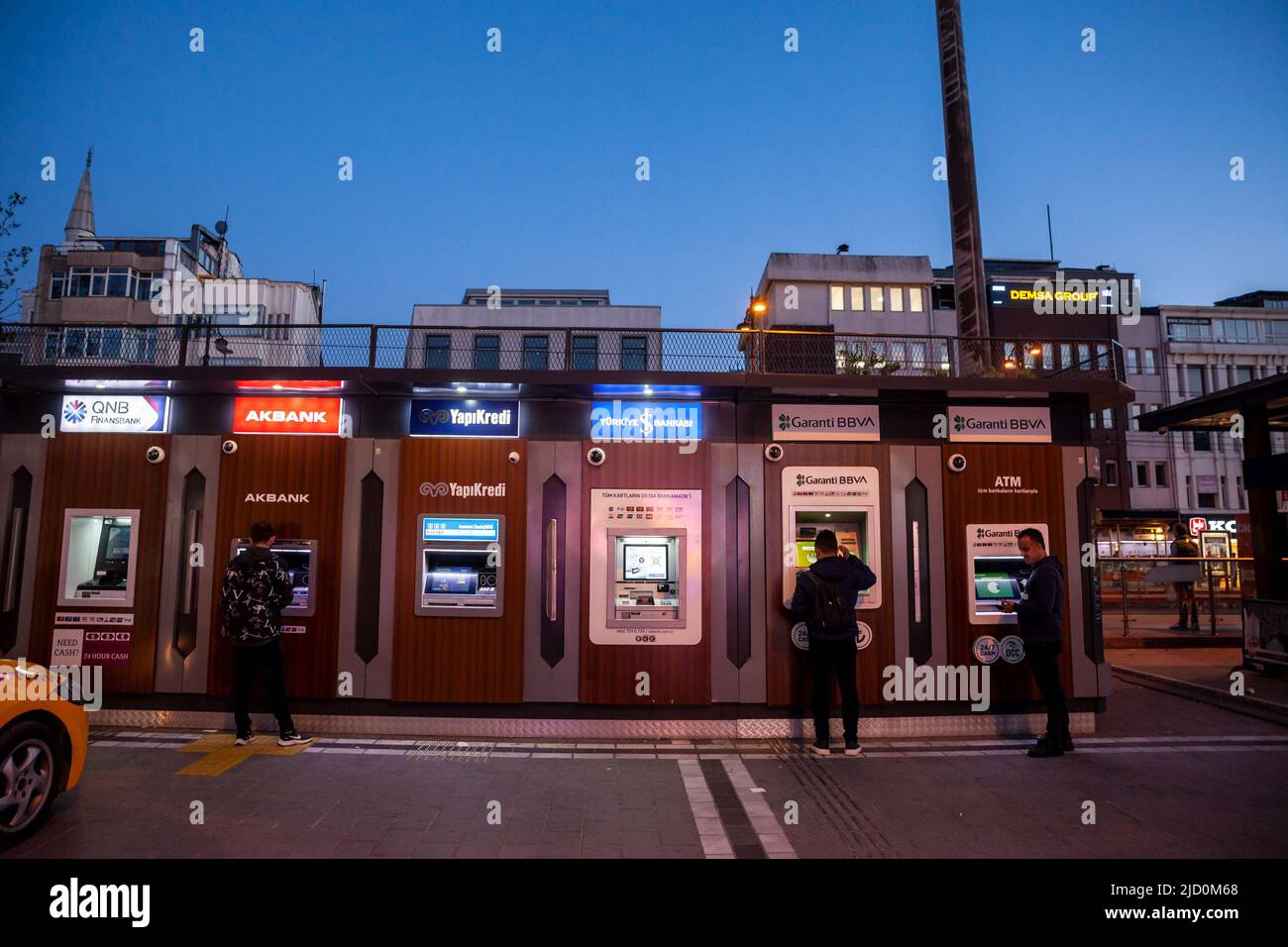 Picture of men, at night, withdrawing cash and money on ATMs in the ...