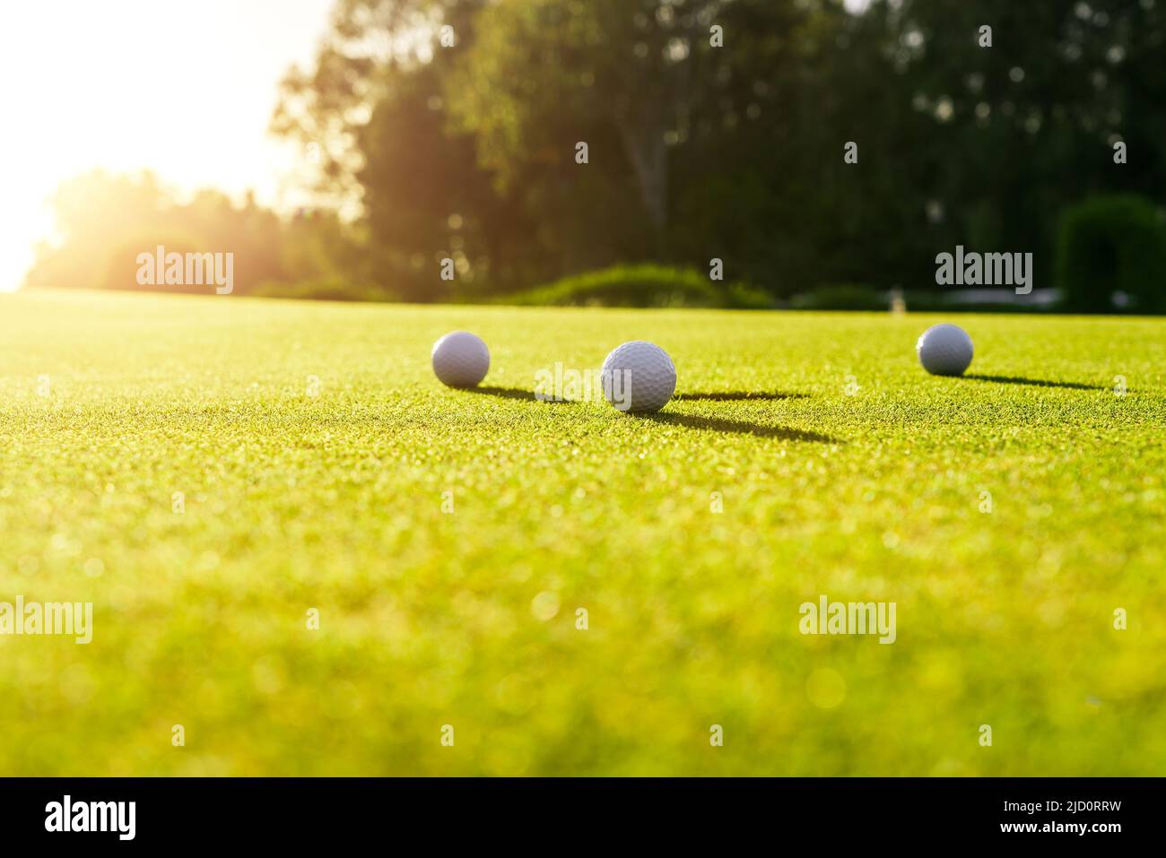 Three golf balls on the green grass near hole on a golf course at ...
