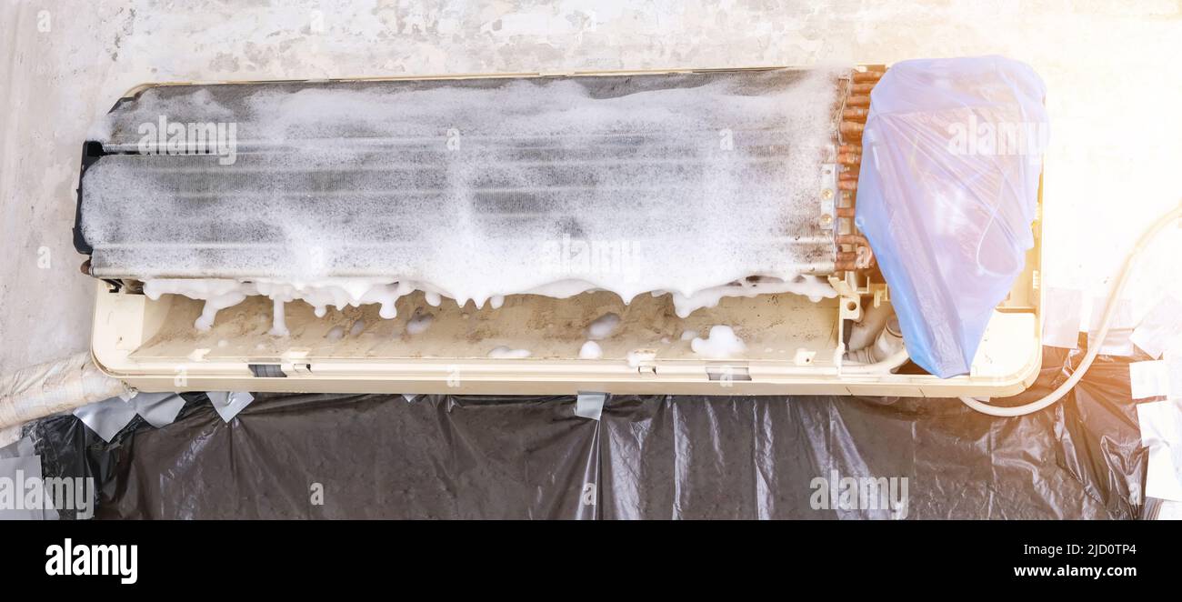 A man sprays special foam to clean air conditioners on the radiator ...