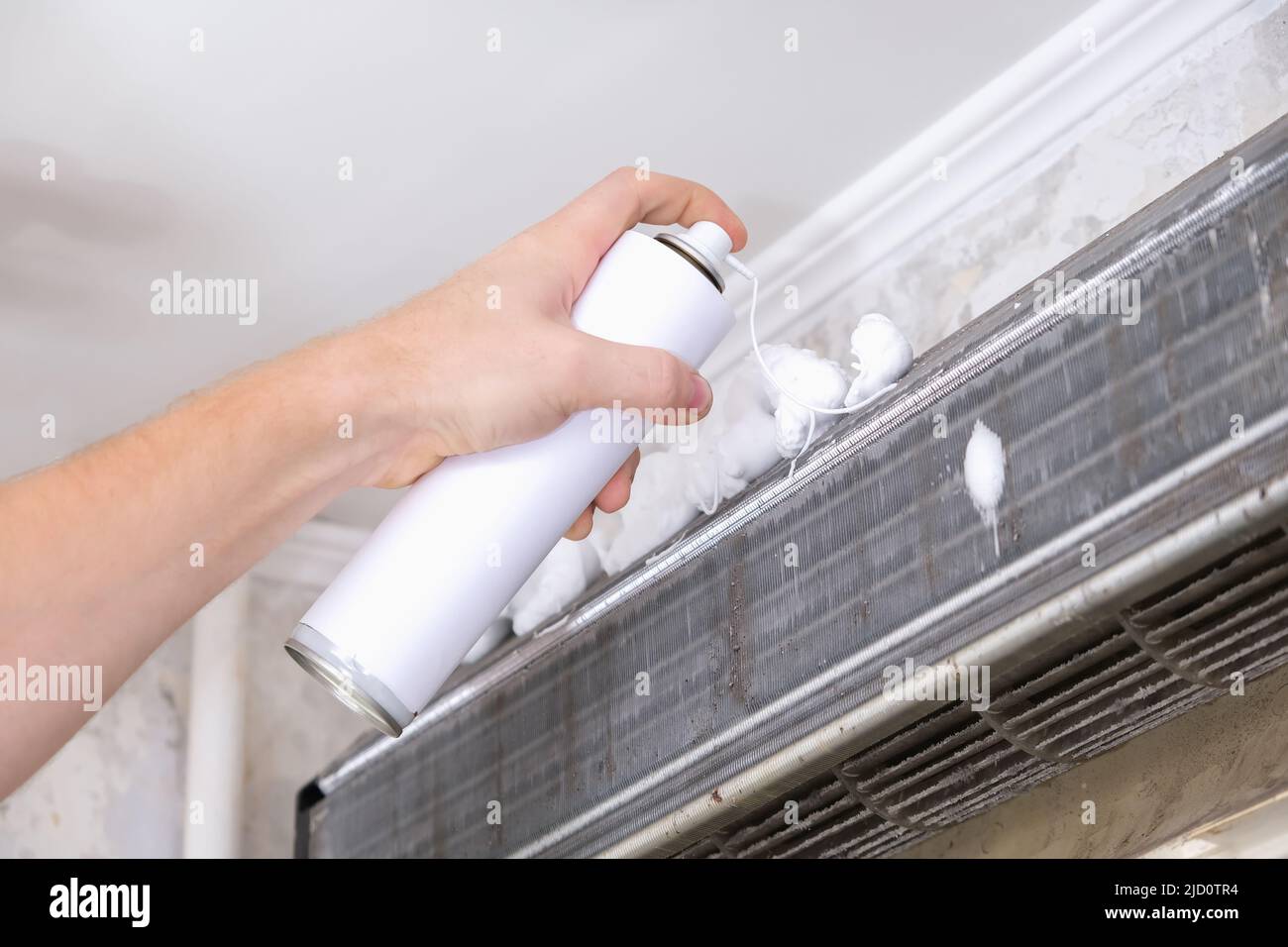 A man sprays special foam to clean air conditioners on the radiator ...