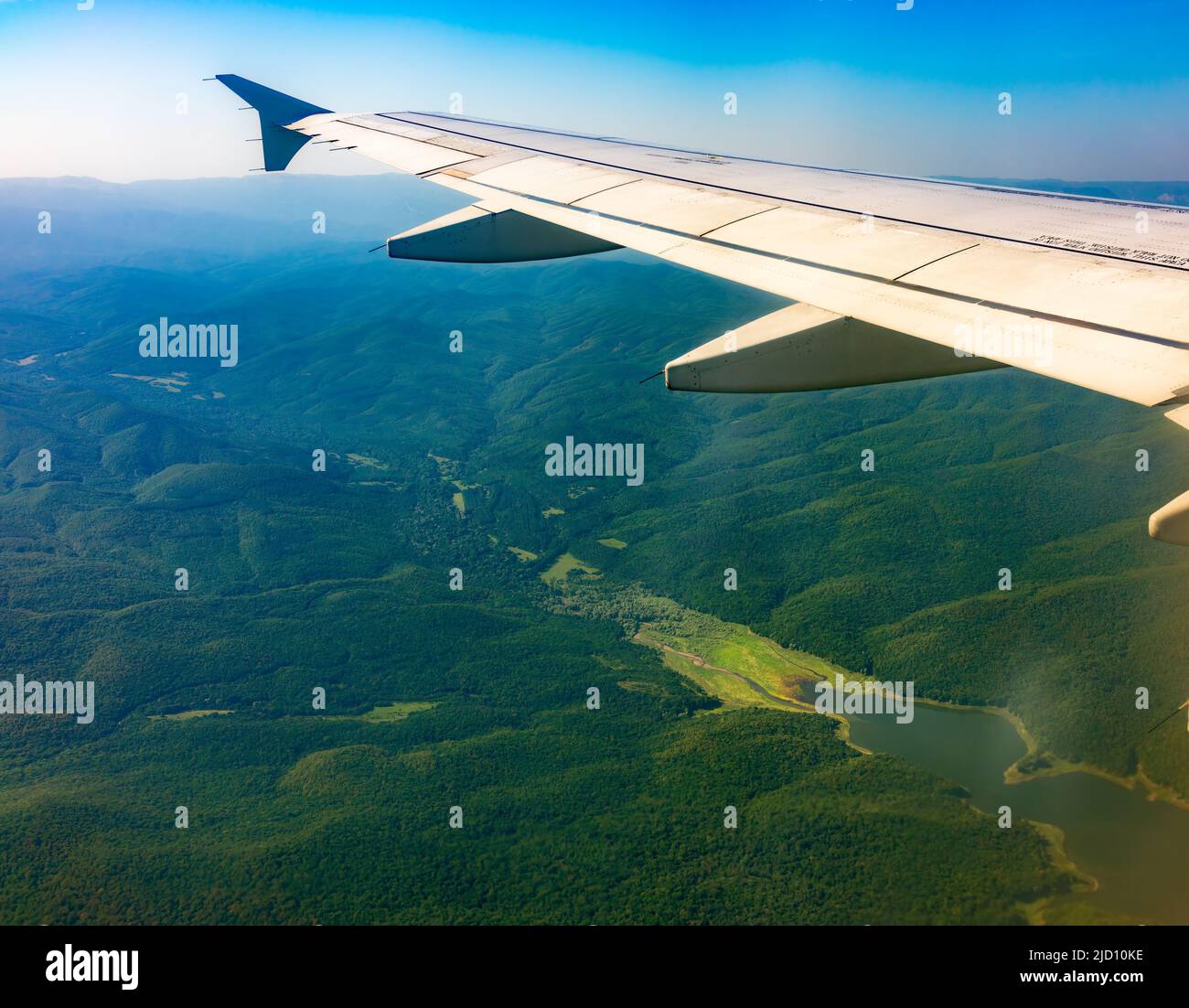 View of airplane wing, blue skies and green land during landing ...