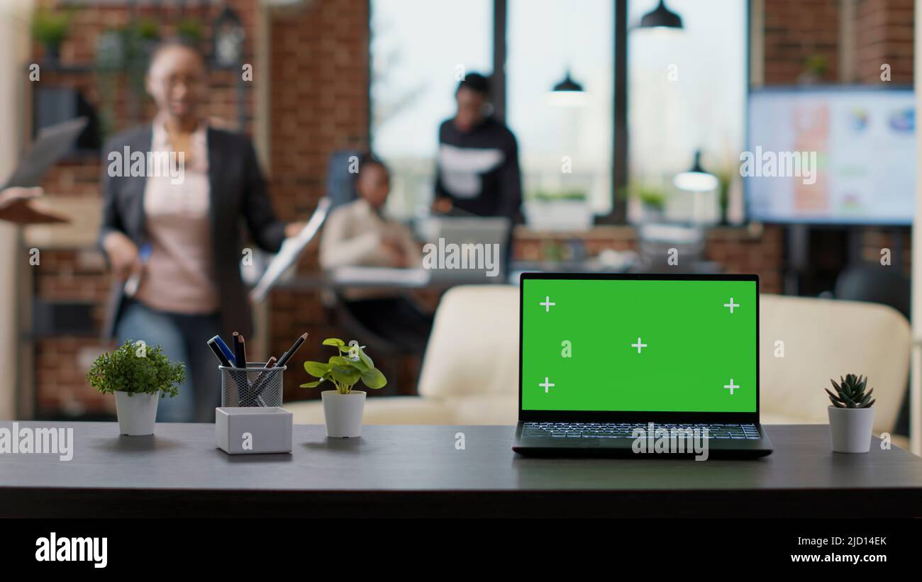Office desk with green screen on laptop computer in workplace, mockup ...
