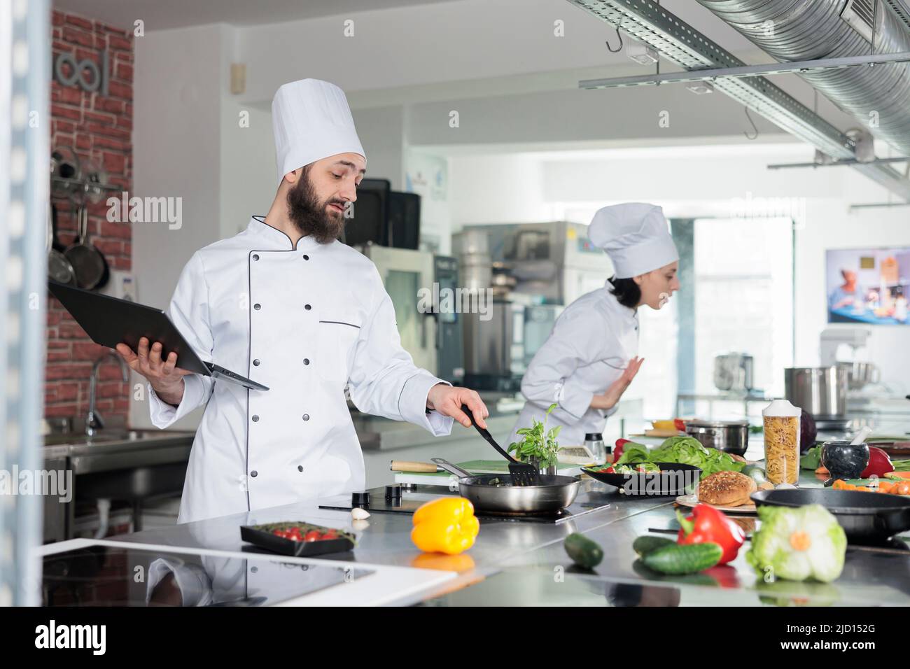 Gourmet cuisine head chef cooking dinner dish while using computer to ...