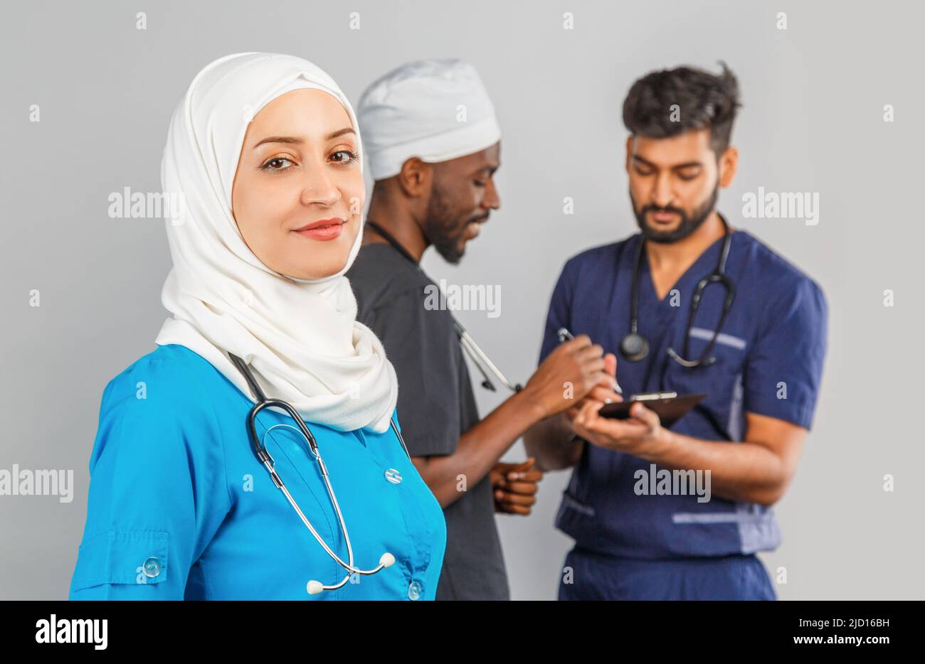 Group of paramedics smiling over gray background. muslim doctor woman ...